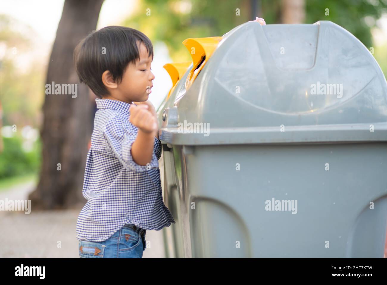 Adorable little boy keep garbage clean to bin in park eco environmennt ...