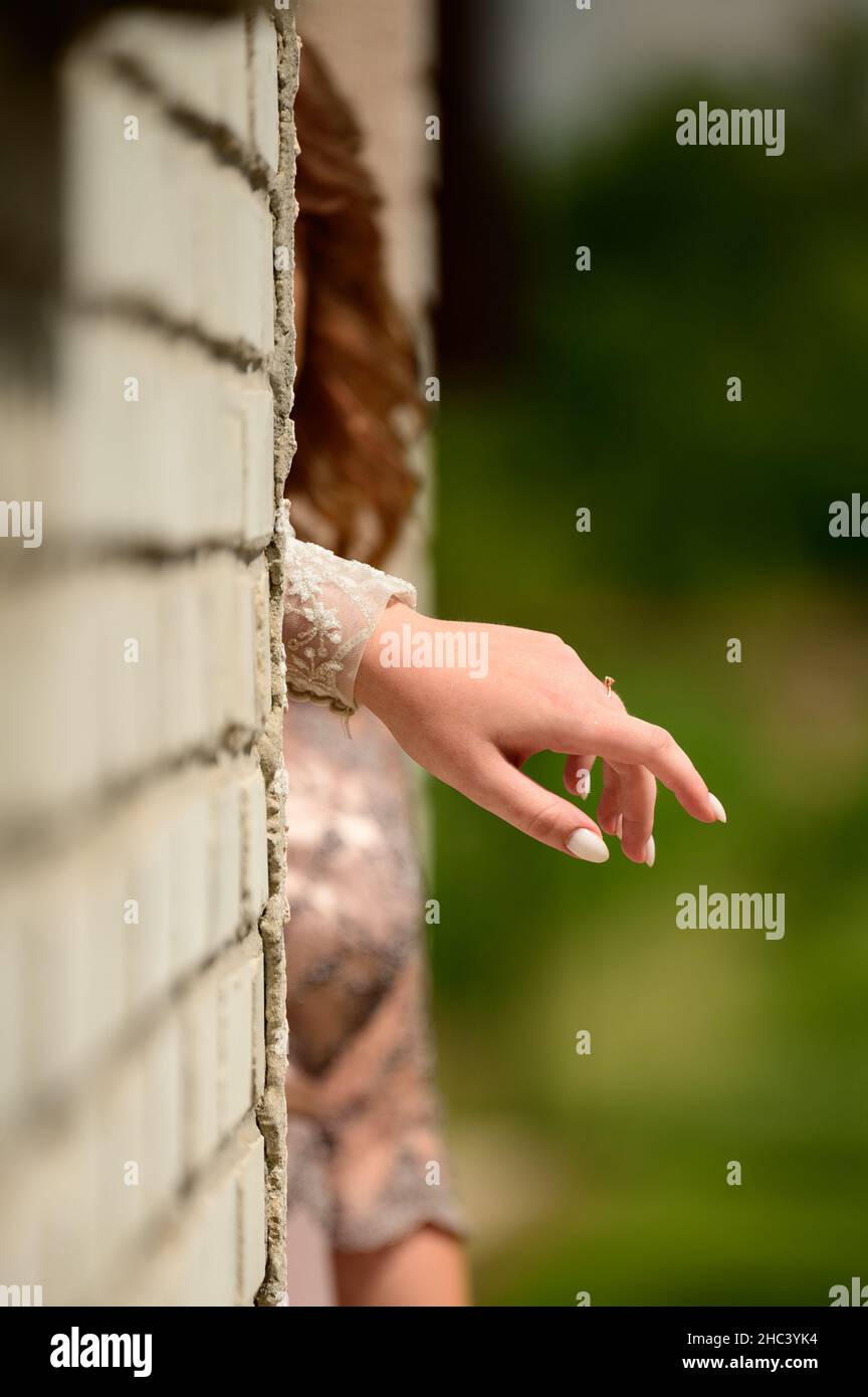 woman stretched out her hand in the doorway, human hand gesture, brick ...