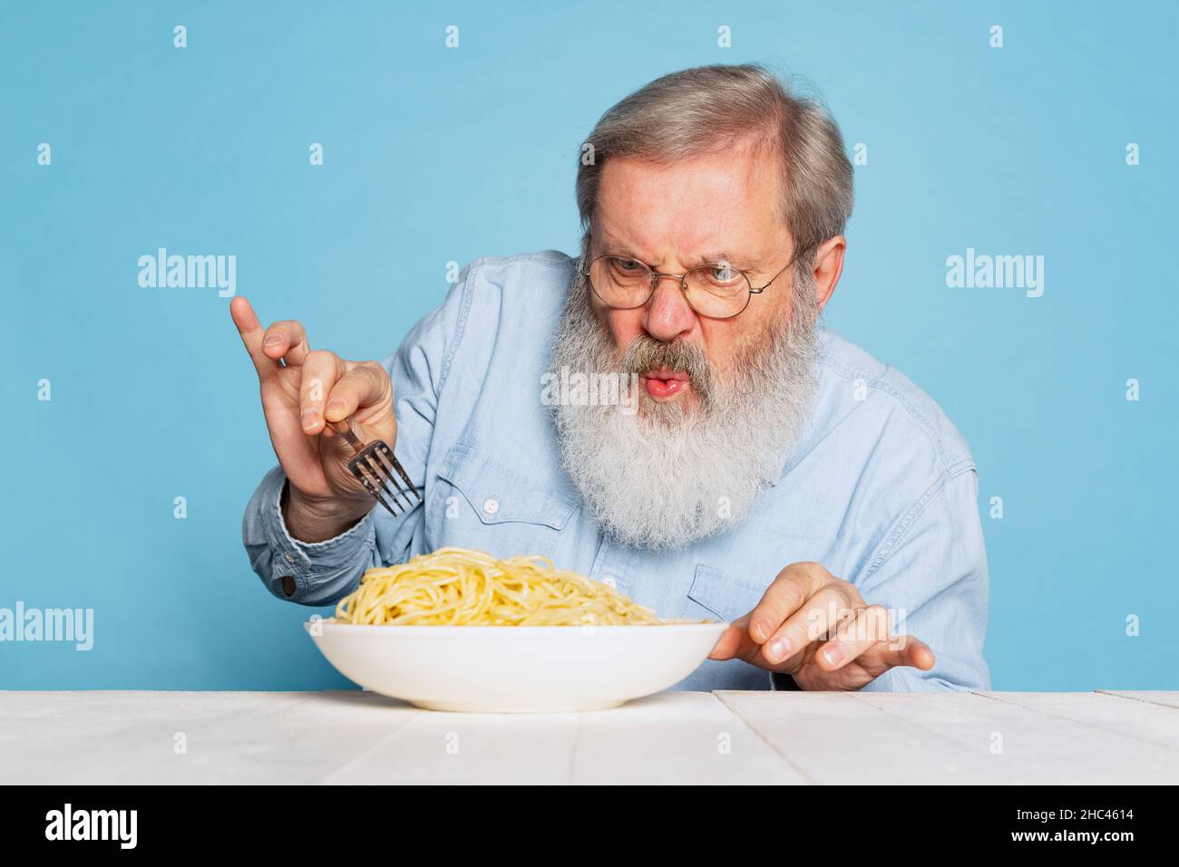 Fastidious senior hairy gray-bearded man tasting large portion of ...