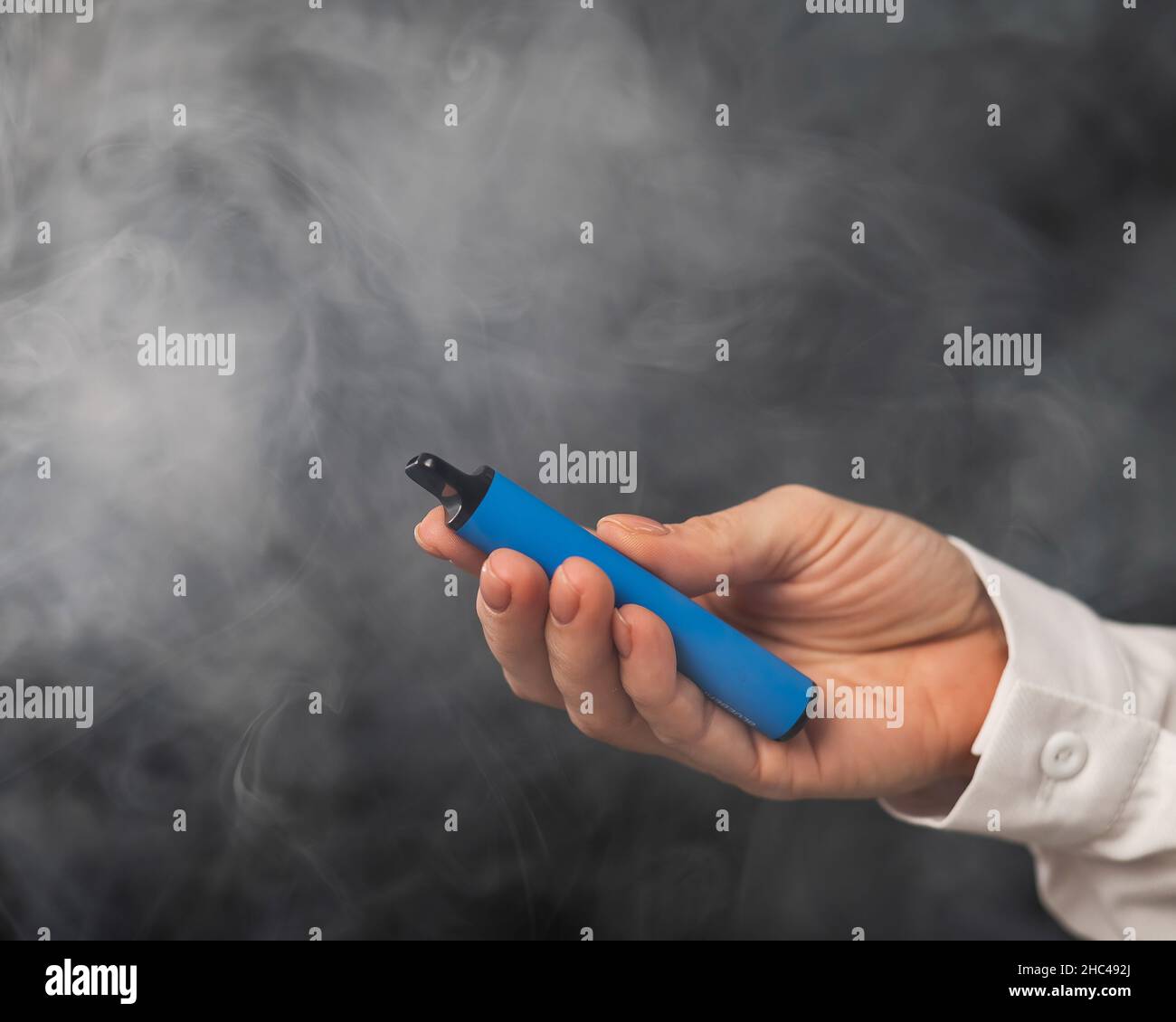 Caucasian woman smokes disposable vape on black background. Alternative ...