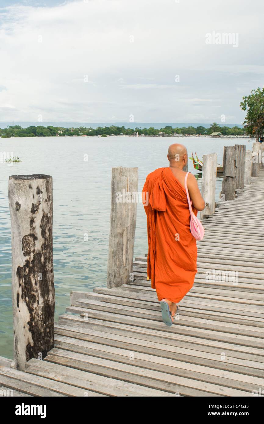 Buddhist monks walking on U-Bein bridge, during sunset, in Taungthaman ...