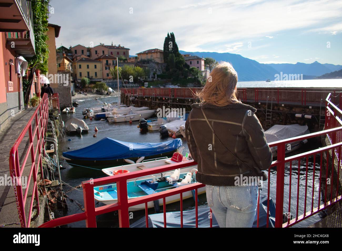 Female tourist overlooking quaint boat harbor outside of Varenna on ...