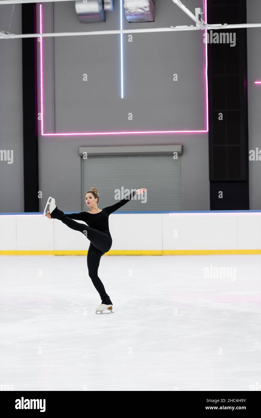 full length of figure skater in black bodysuit skating with ...