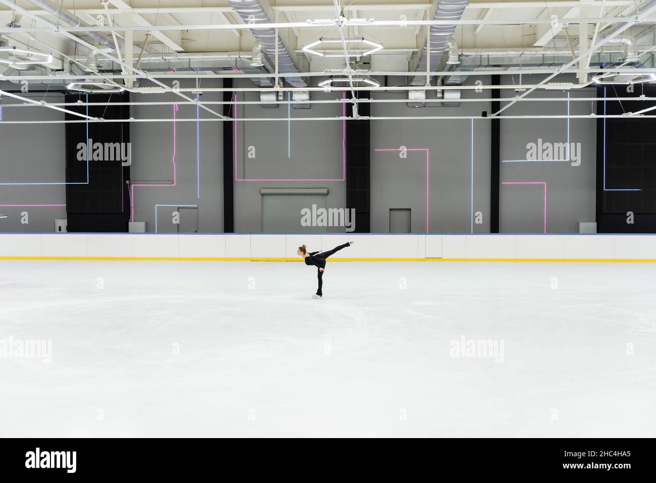 side view of figure skater in black bodysuit skating in professional ...
