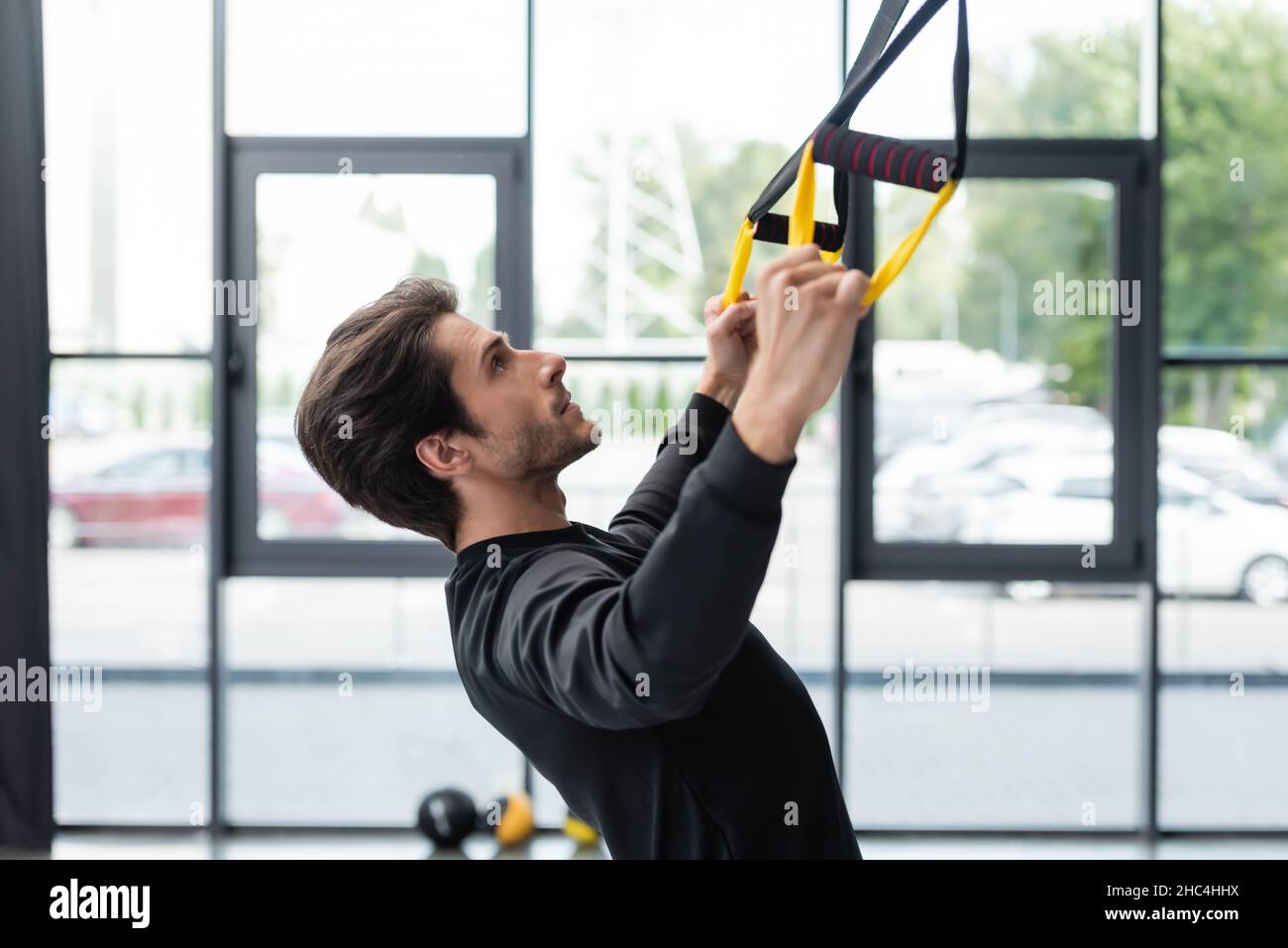 Side view of sportsman training with suspension straps in gym Stock ...