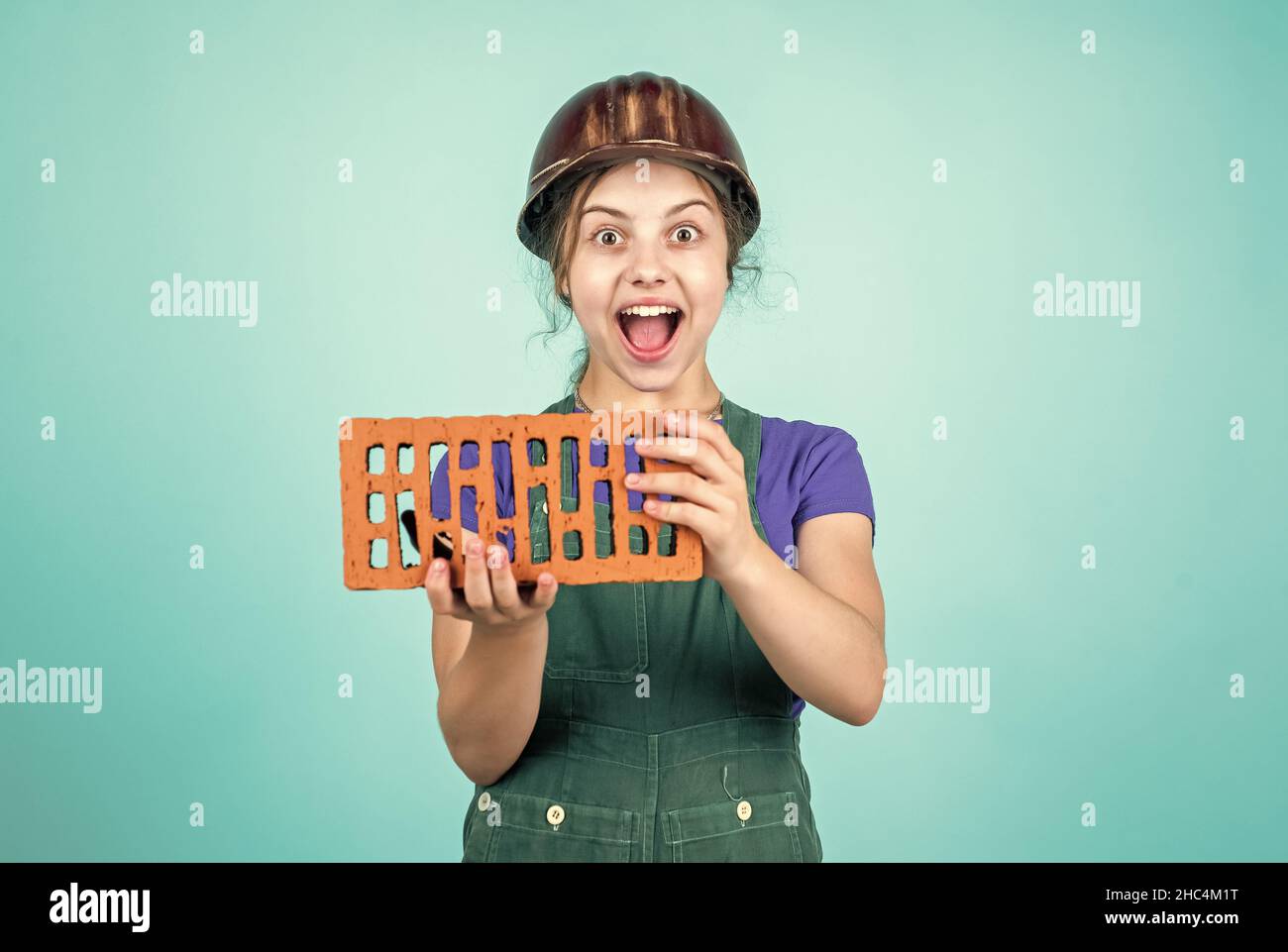 cheerful child laborer using building uniform and brick, wow Stock ...