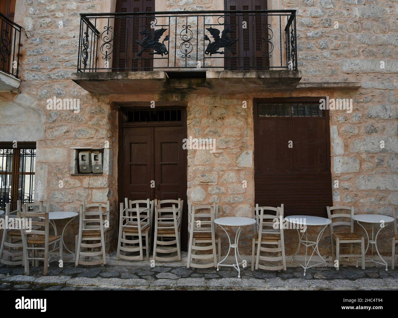 Traditional Greek tavern with a stone wall, wooden door and windows, a ...