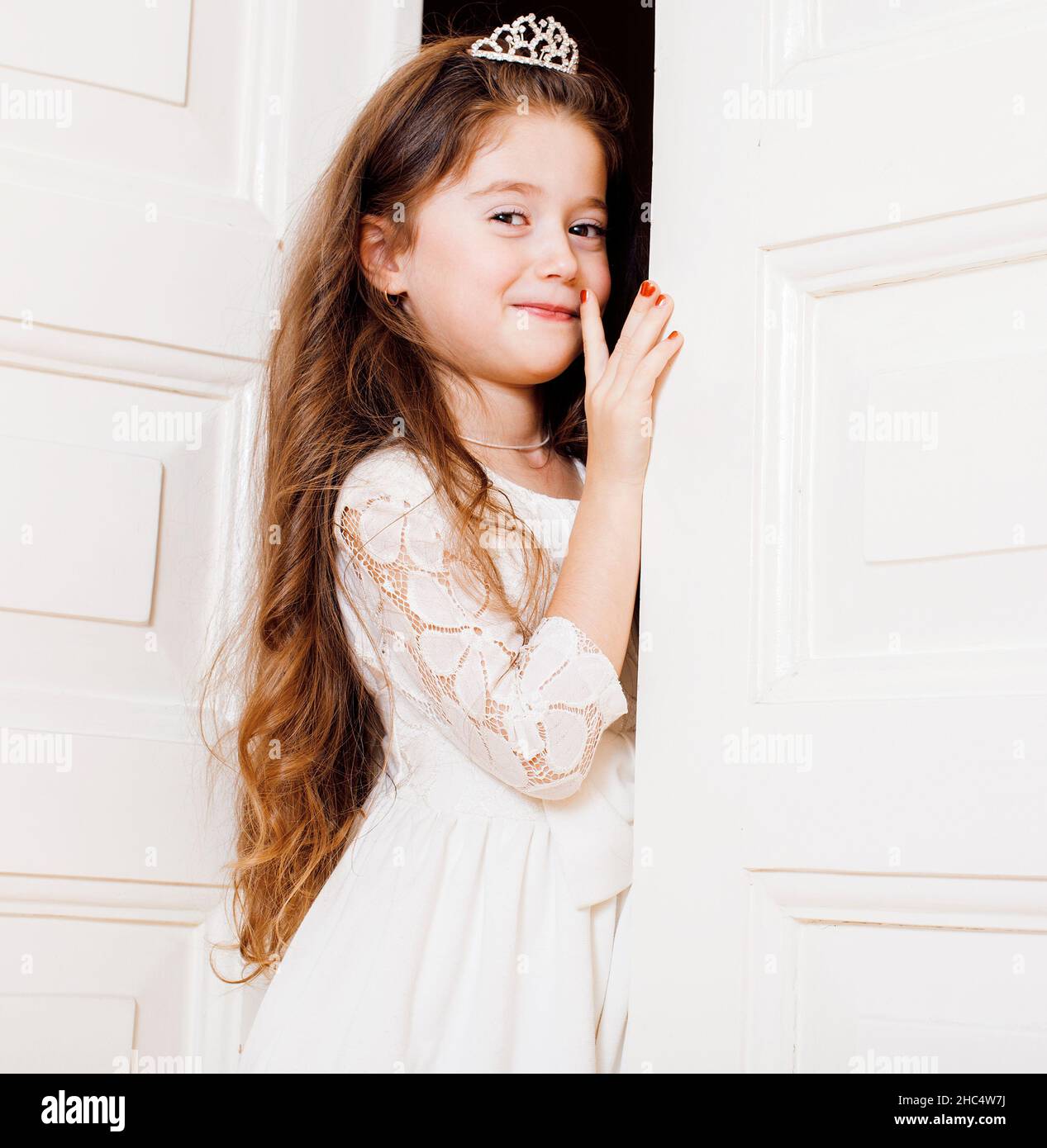little cute girl at home, opening door well-dressed in white dress ...