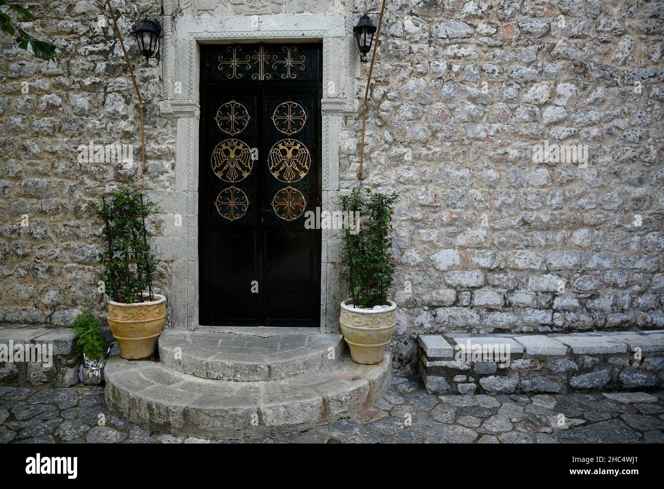 Traditional Greek Orthodox church facade with a stone wall and steps ...