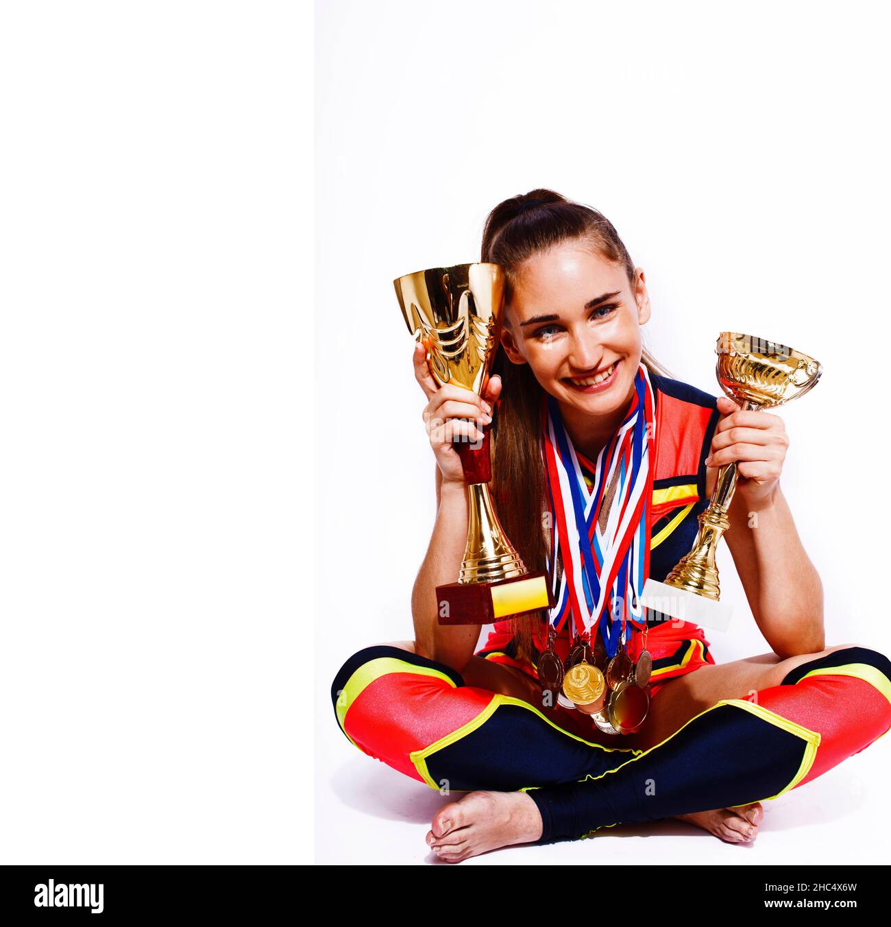 young smiling cheerleader girl with golden cups and price medals ...