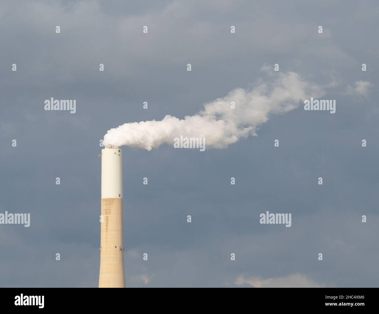 An industrial chimney emitting thick, white smoke, polluting the air ...
