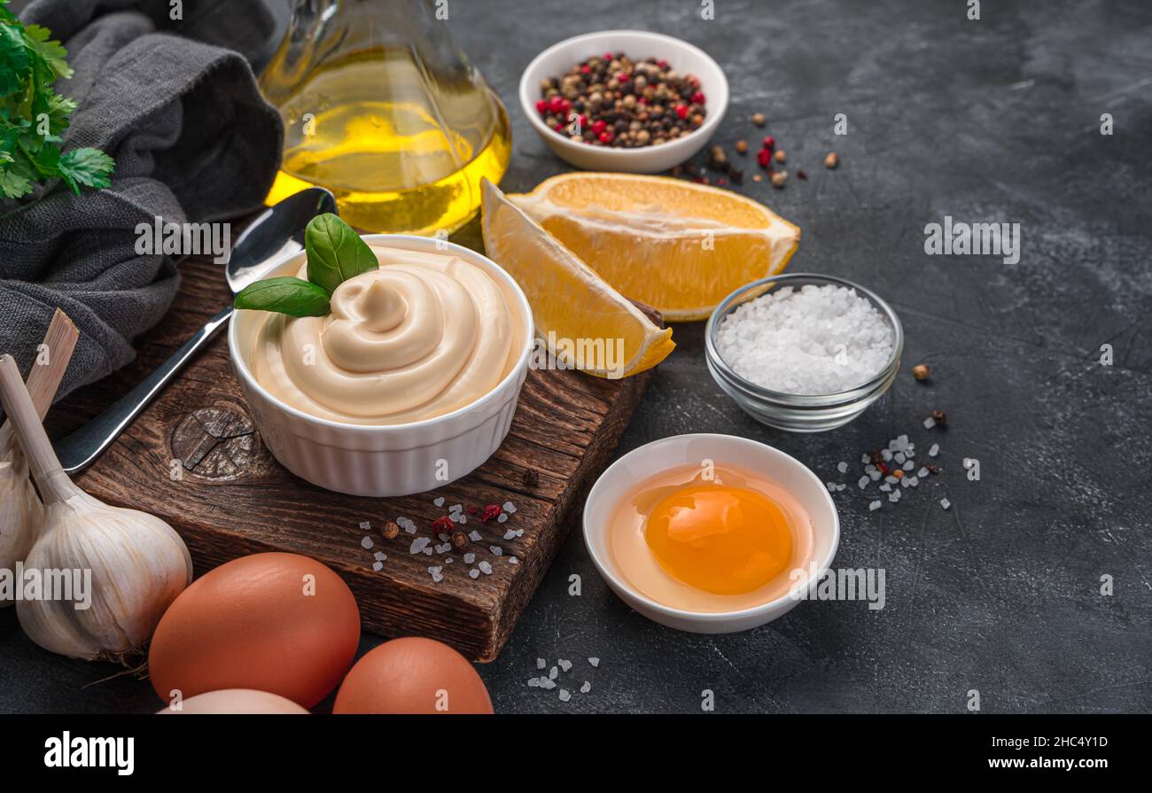 Fresh mayonnaise on a dark background with ingredients for its ...