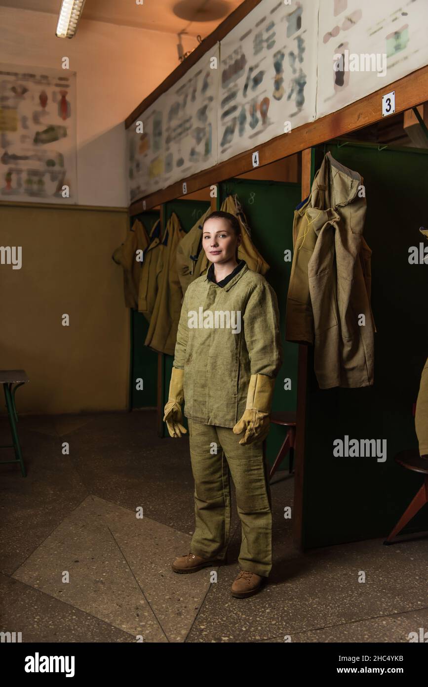 Welder in uniform and gloves looking at camera in dressing room of ...