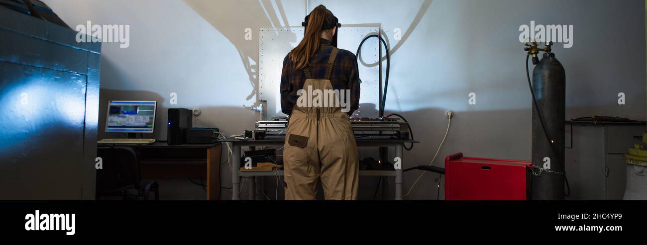 Back view of welder in overalls working near gas cylinder in factory ...