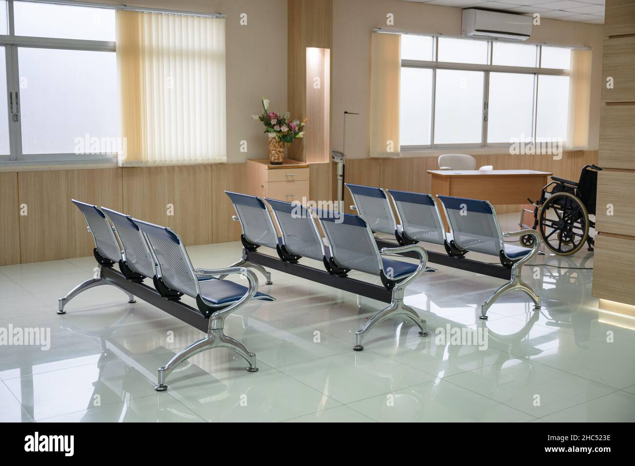 Row of blue empty chairs and wheelchair in waiting room at hospital ...