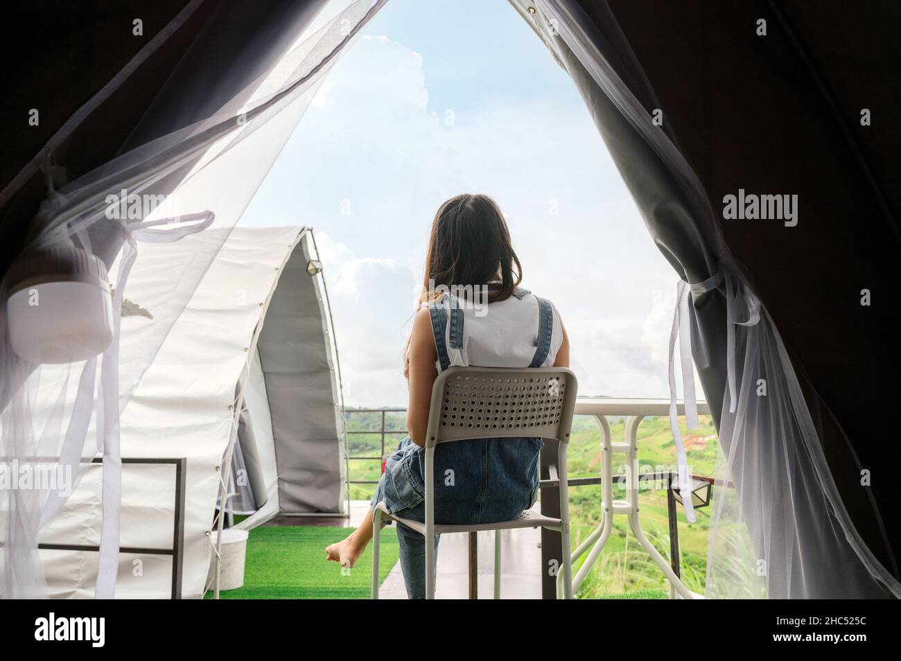 Back view of asian woman sitting on front a tent among the mountain in ...
