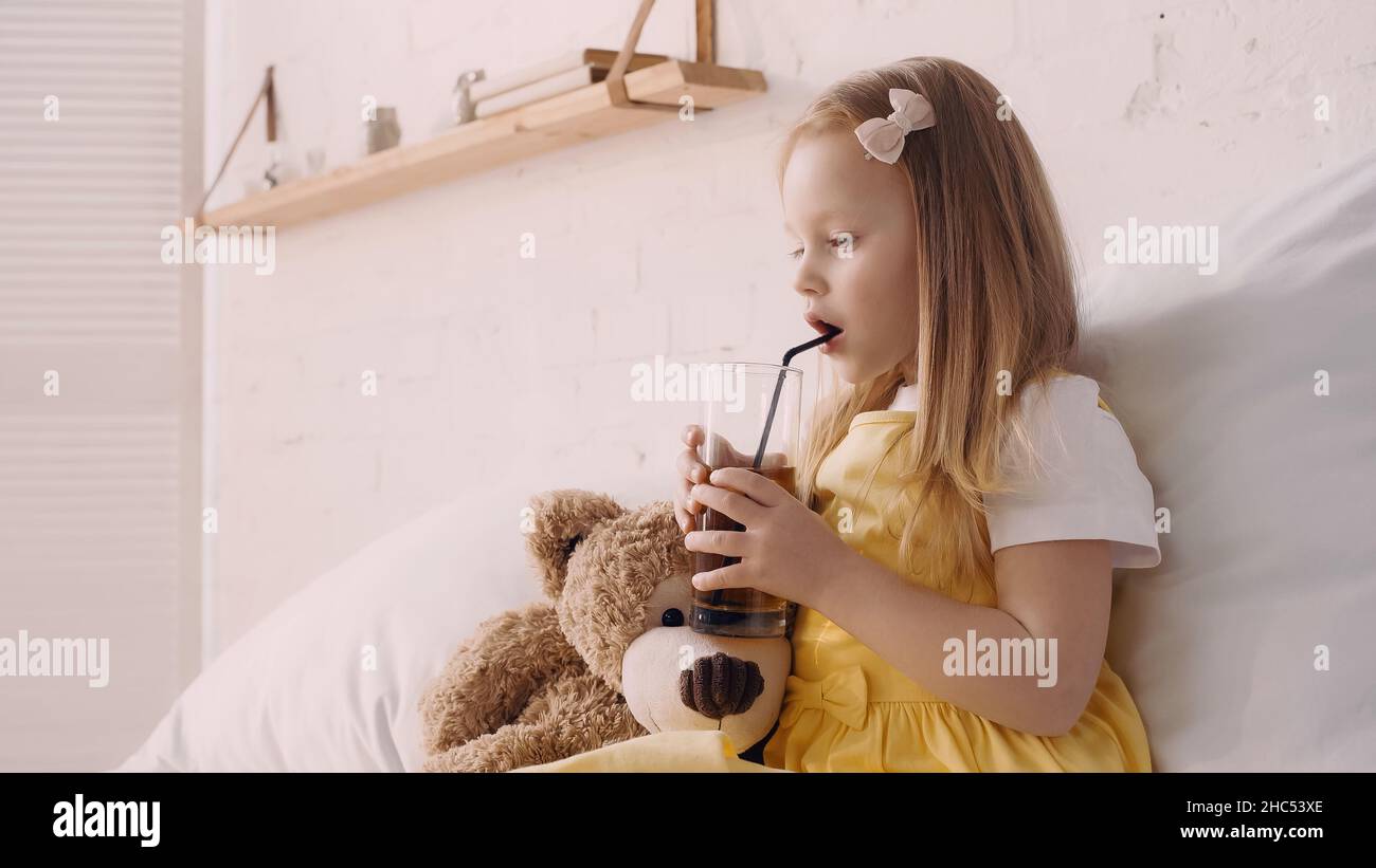 Kid holding glass of juice near teddy bear on bed Stock Photo - Alamy