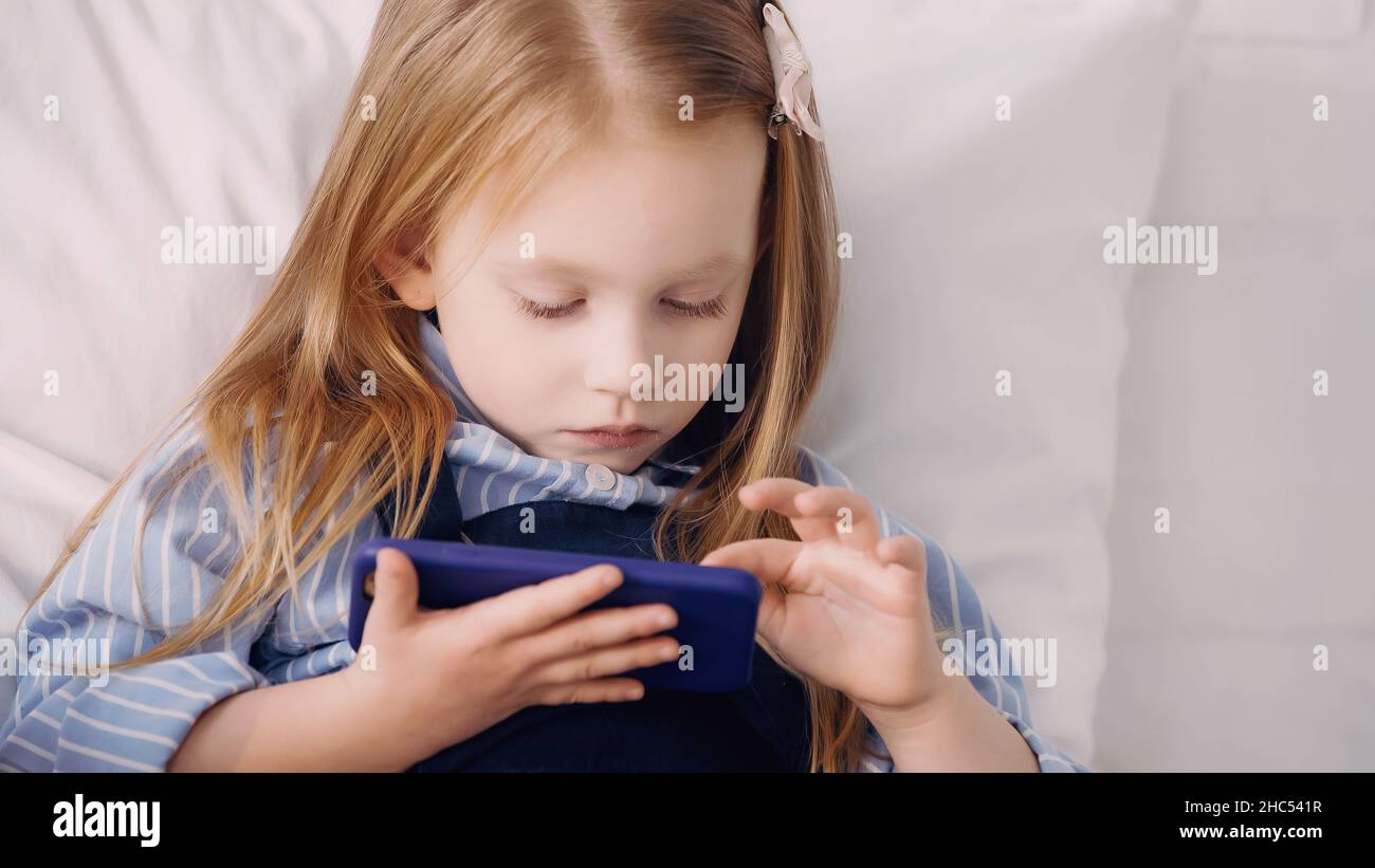 Child using mobile phone on bed at home Stock Photo - Alamy