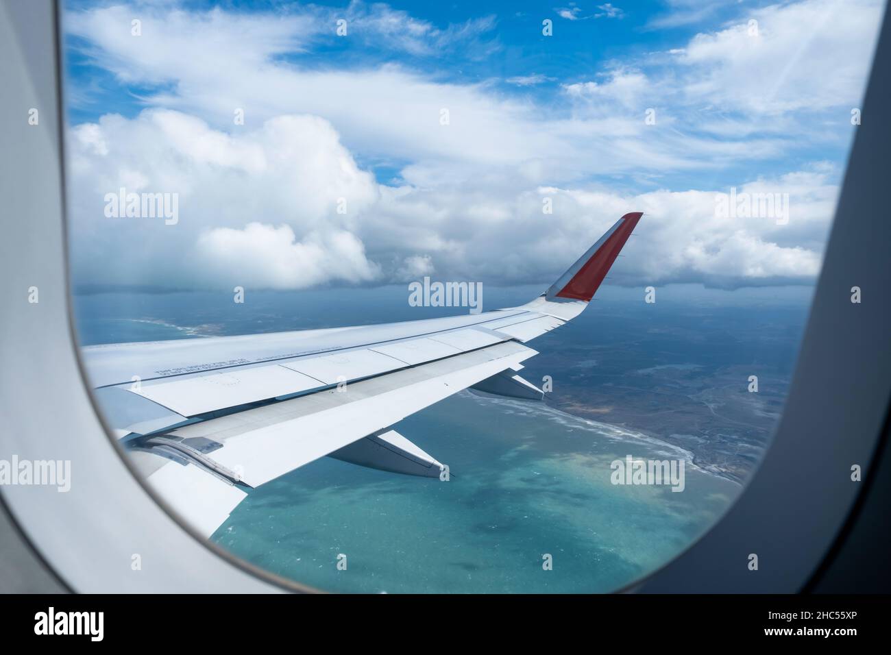 Classic image through aircraft window onto wing. Flight view over sea ...