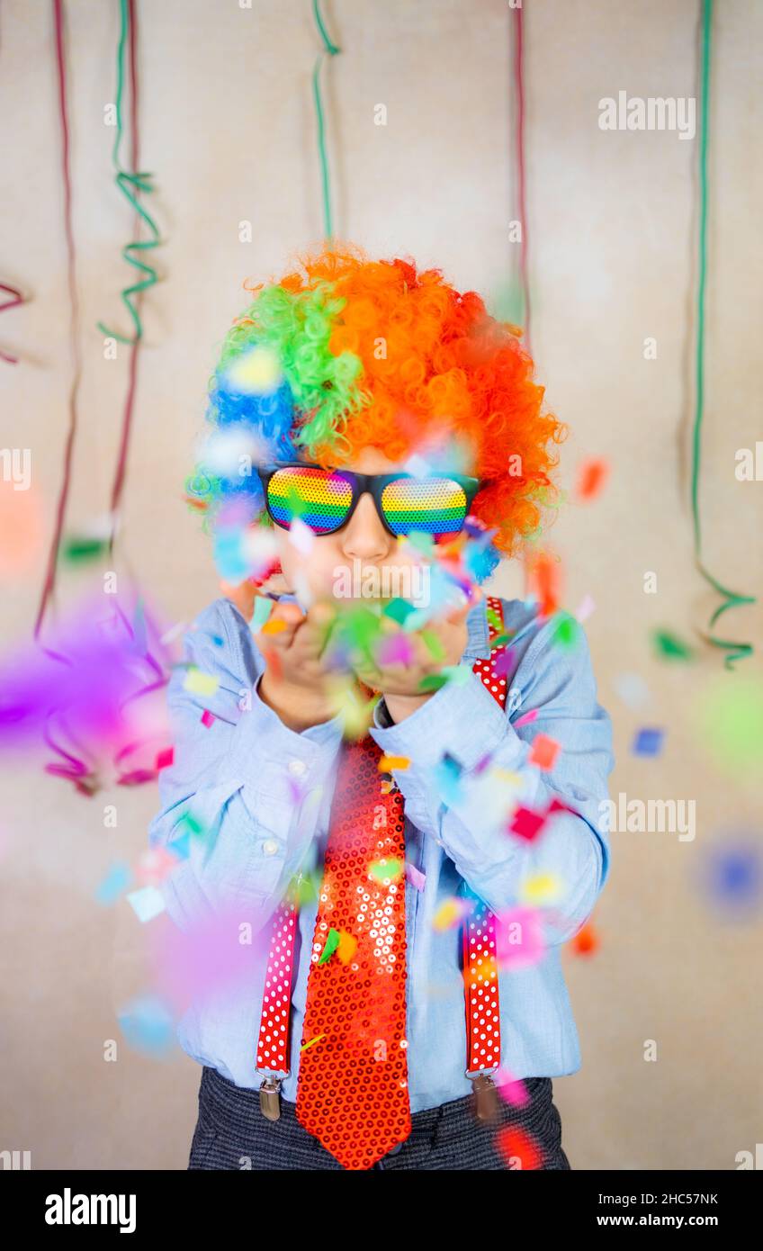 Funny boy blowing confetti at carnival Stock Photo - Alamy
