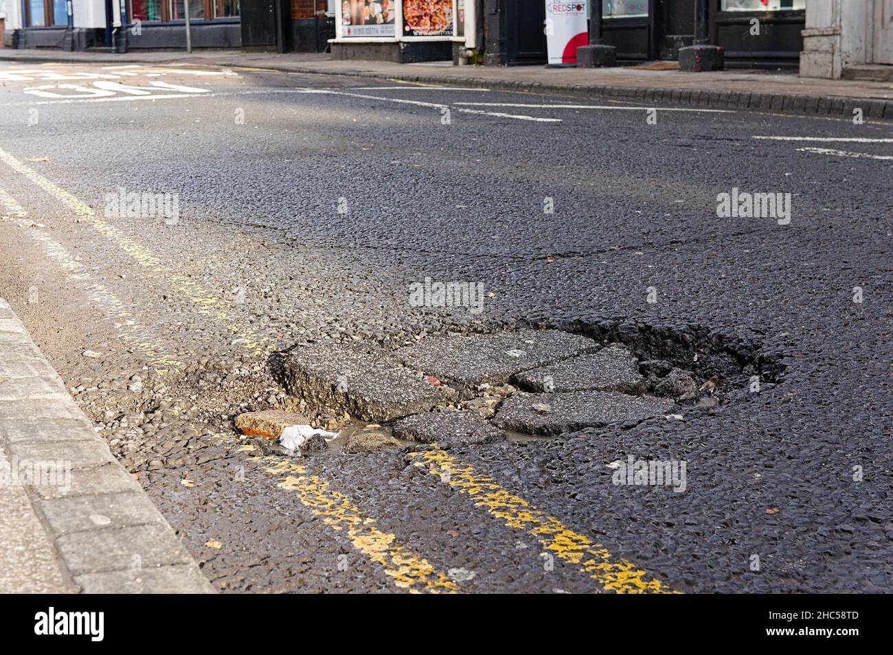 Low angle view of a large pothole causing damage to the side of a road ...