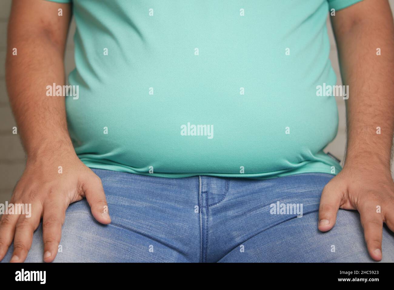 fat man with a big belly while sitting on a chair Stock Photo - Alamy