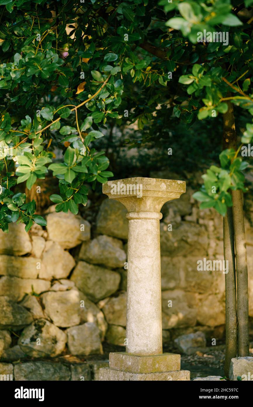 Simple stone column in the garden near the stone wall Stock Photo - Alamy