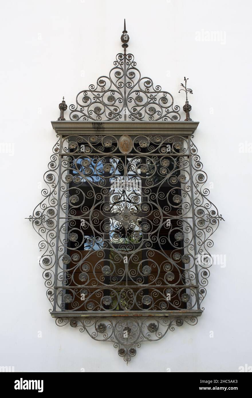 Elaborate, old-fashioned wrought iron window and frame in a white ...