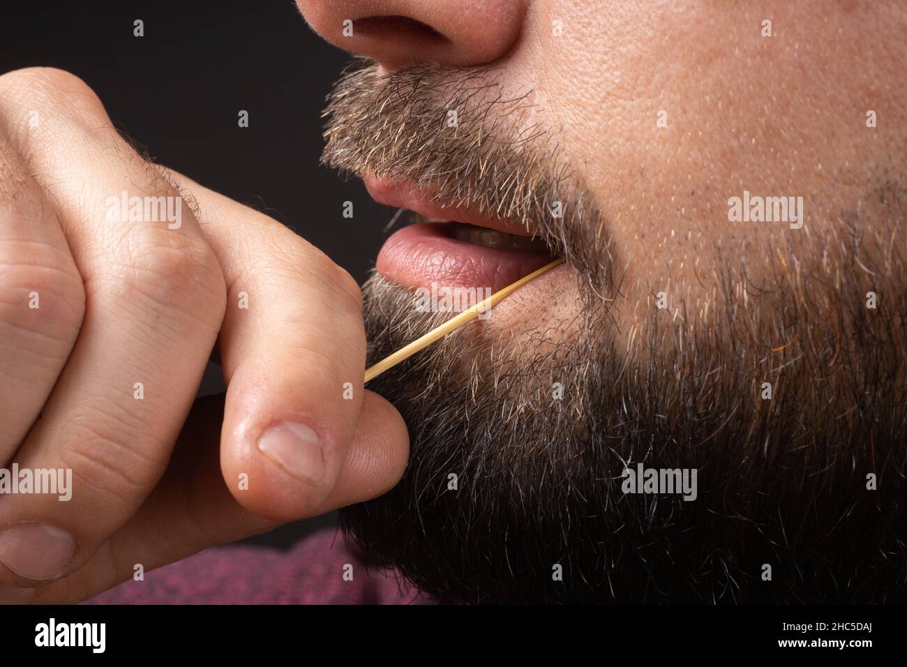 Close up bearded man clean teeth from food stuck her teeth with ...