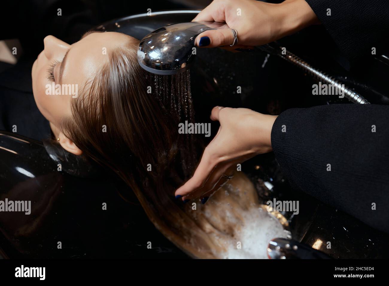 Hairdresser in beauty salon washes his client hair, before procedure of ...