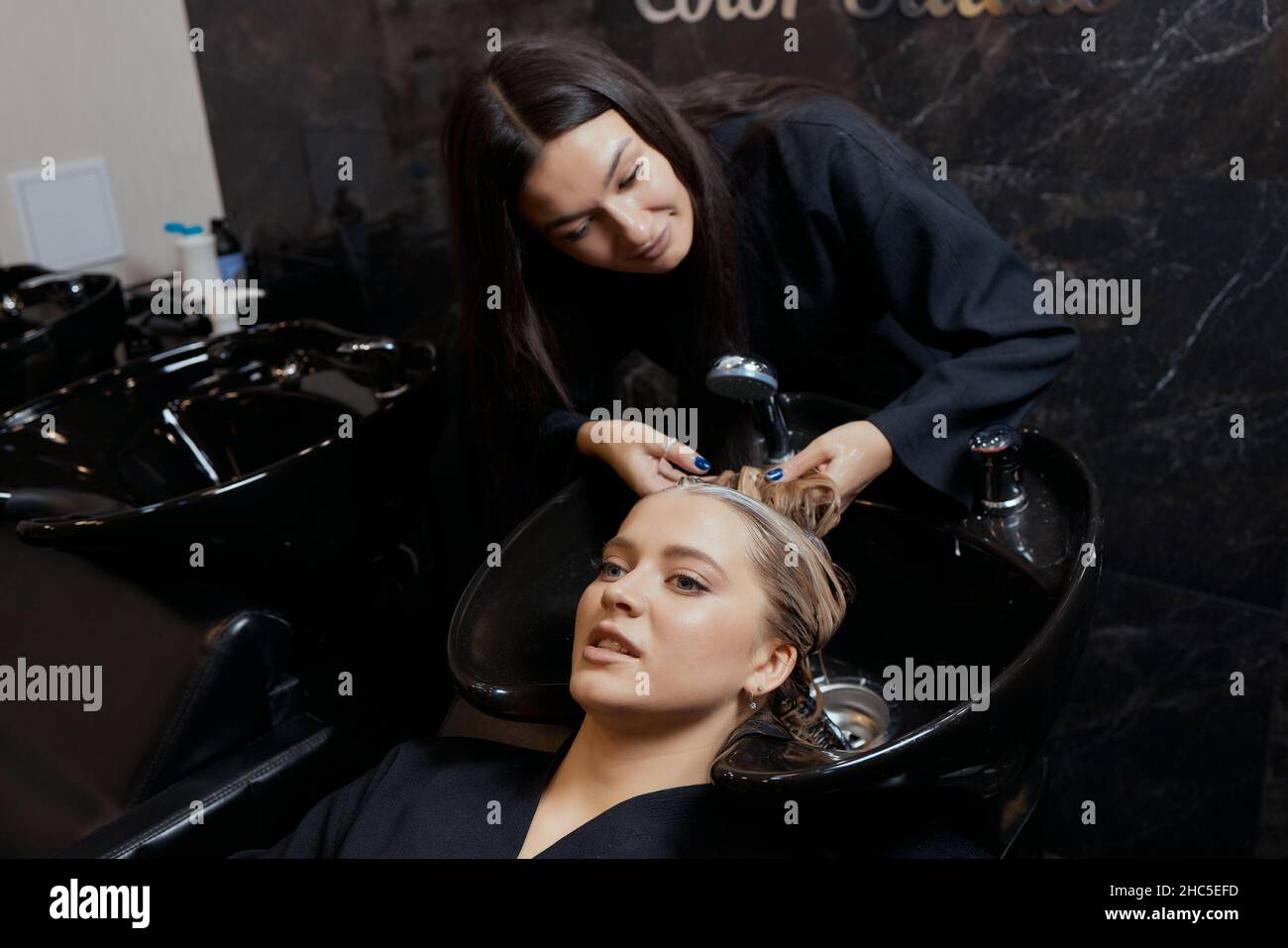 Hairdresser in beauty salon washes his client hair, before procedure of ...