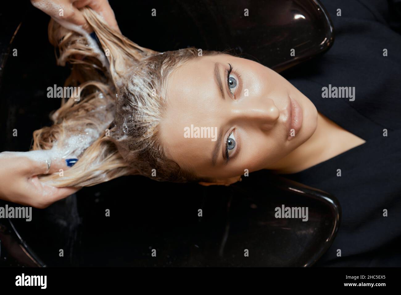 Hairdresser in beauty salon washes his client hair, before procedure of ...