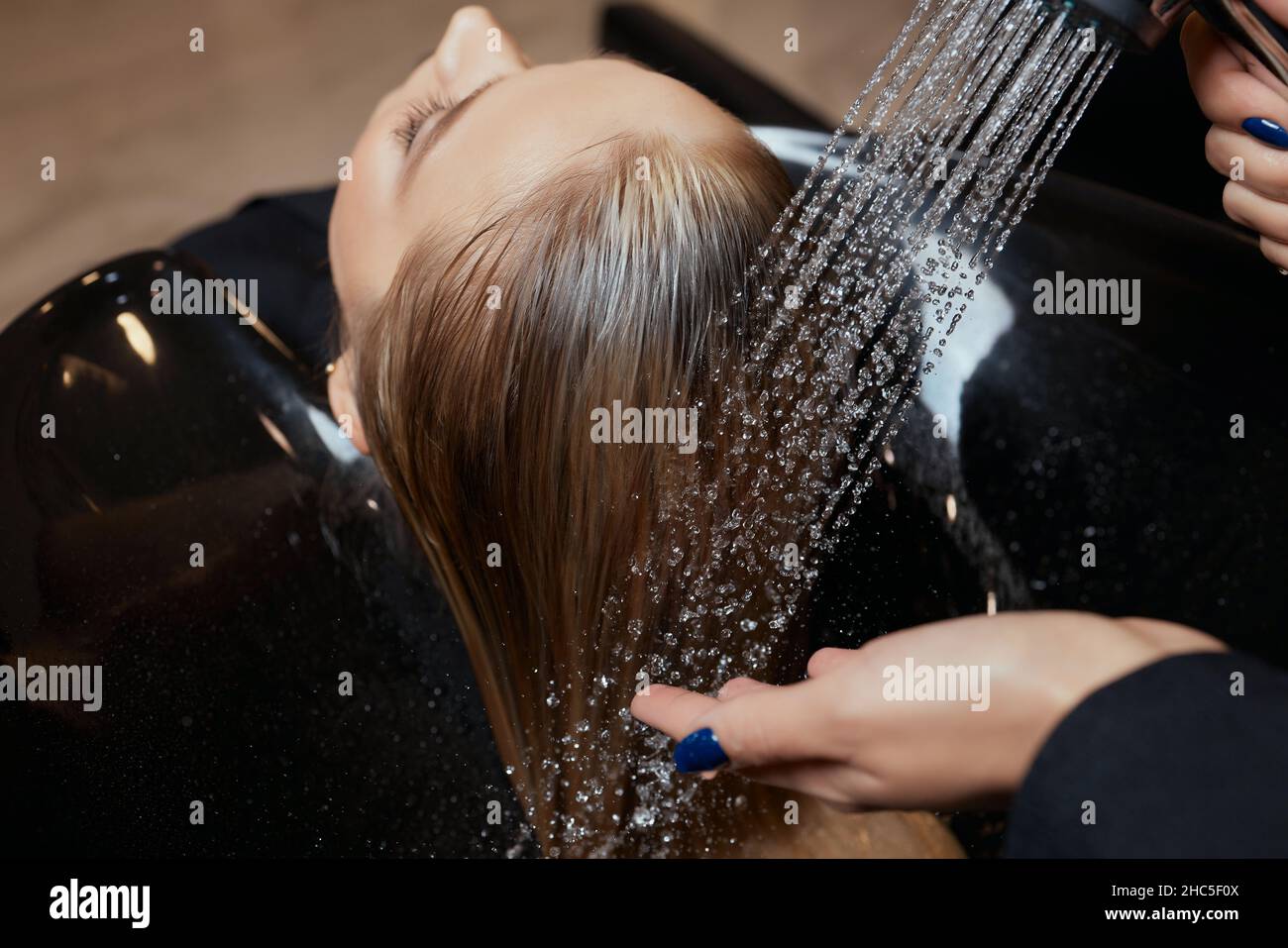 Hairdresser in beauty salon washes his client hair, before procedure of ...