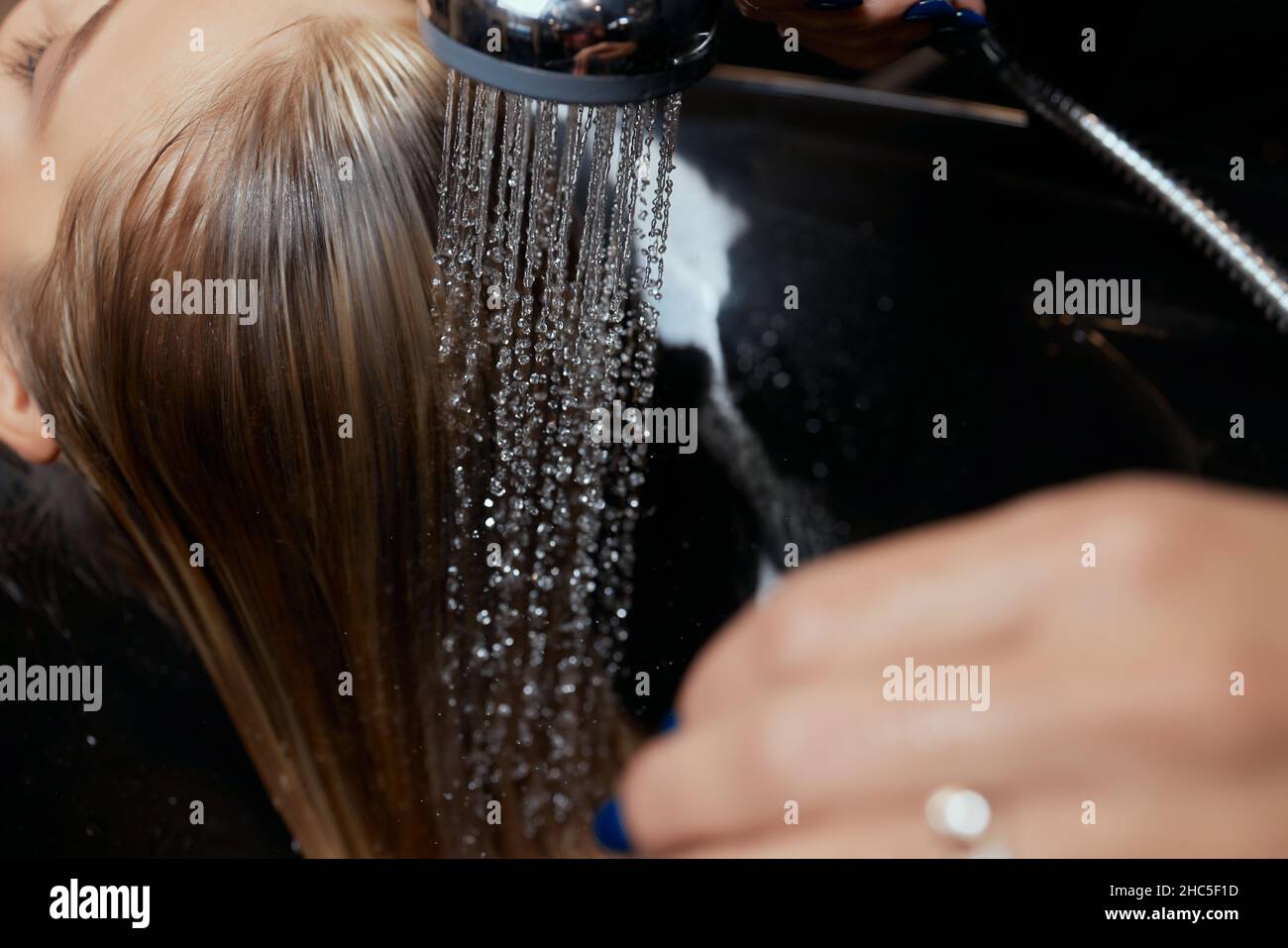 Hairdresser in beauty salon washes his client hair, before procedure of ...