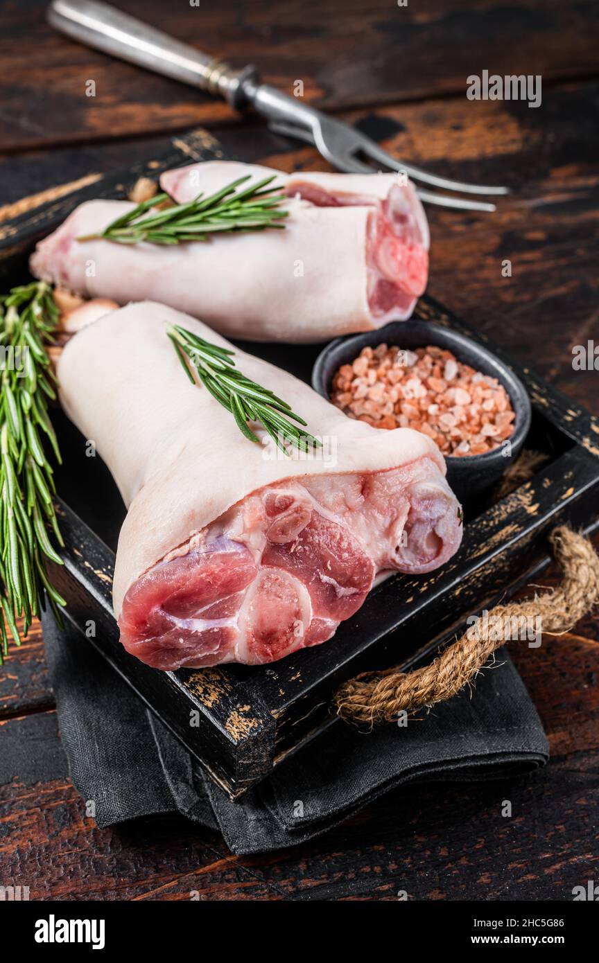 Uncooked Raw pork hoof, knuckle, feet in a wooden tray with herbs ...