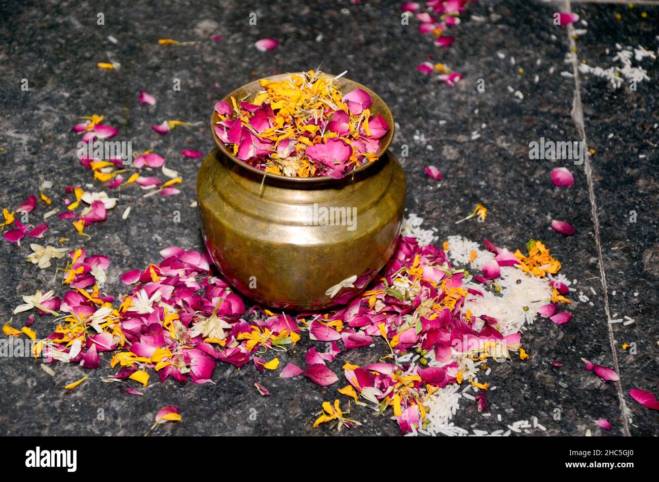 Multicolored flower petals filled in a bronze jar surrounded with ...