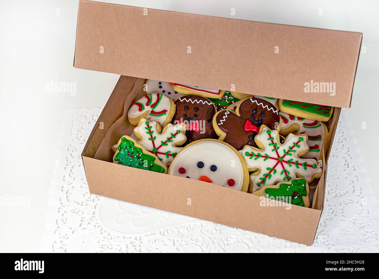 Variety of Christmas sugar cookies in a cardboard box on white doily ...