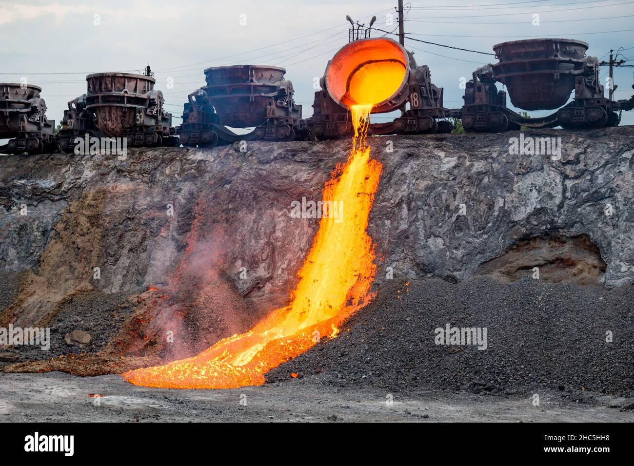 Colorful stream of molten metal at a steel mill. Blast furnace slag at ...