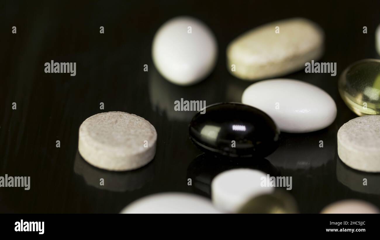 A lot of tablets on the black background. colorful pills and needle on ...