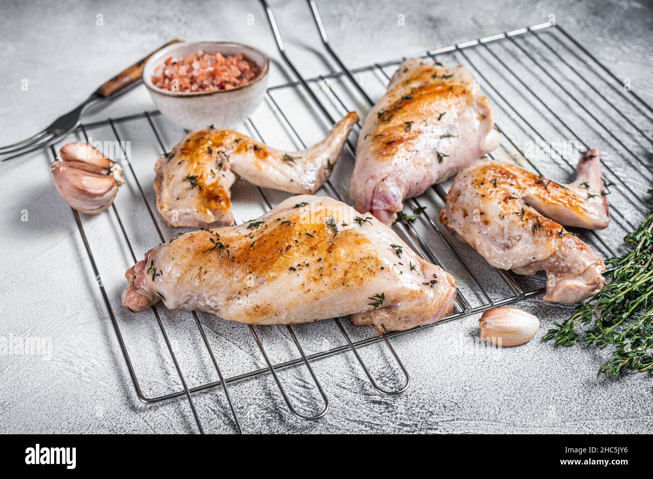 Baked rabbit legs on a grill with thyme. White background. Top view ...