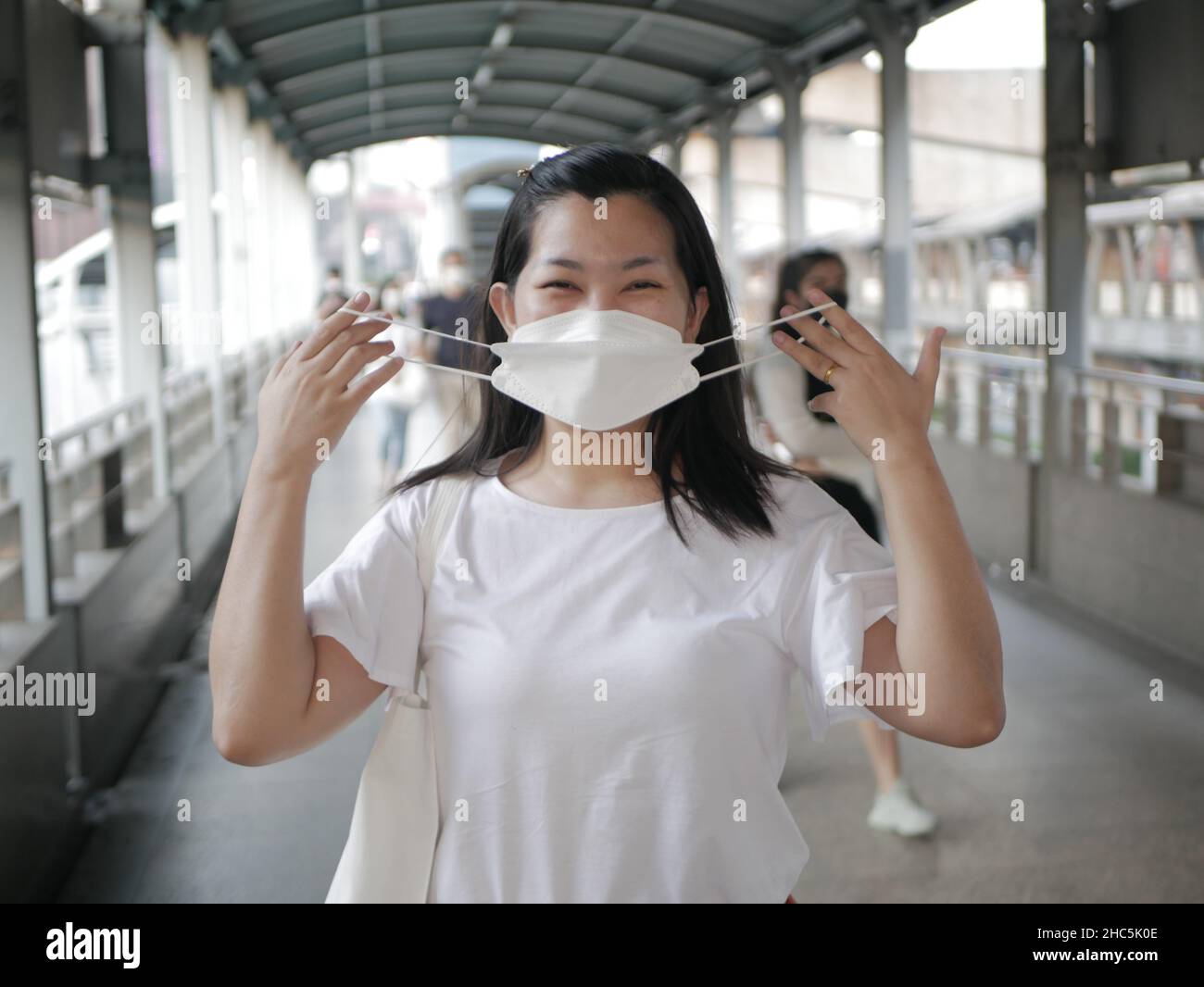 A portrait of a Southeast Asian female holding a medical mask in front ...