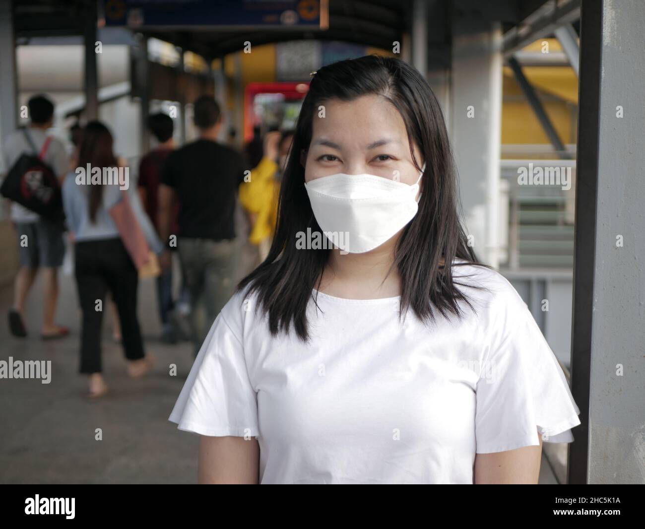 A Southeast Asian female wearing a medical mask in the overground ...