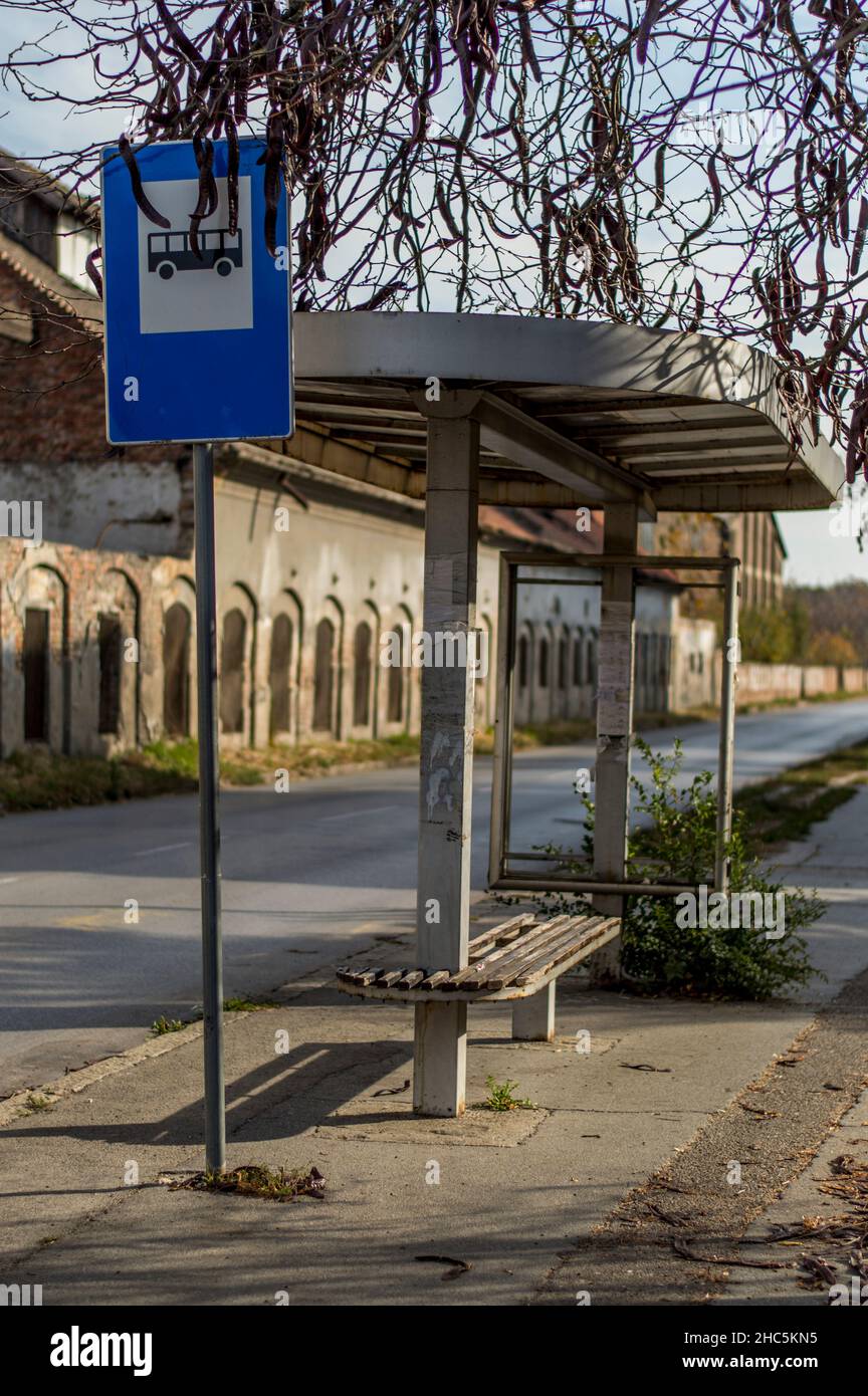 Empty bus station shelter with a wooden painted bench Stock Photo - Alamy