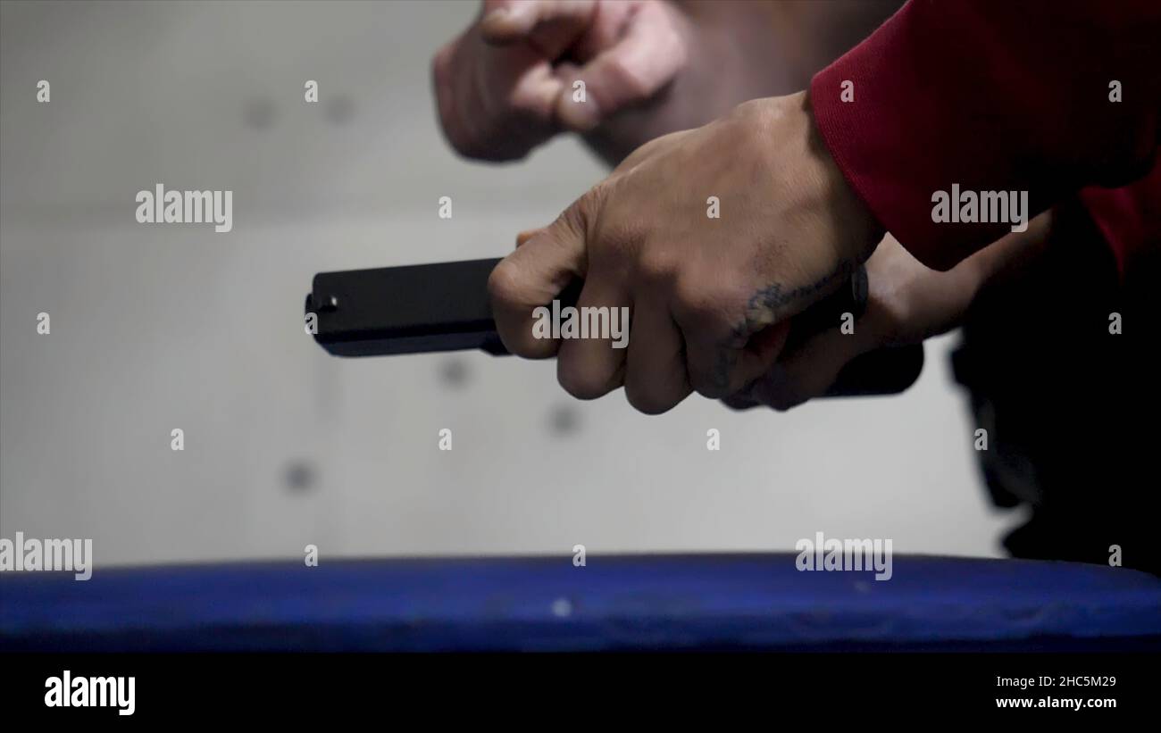 Trainer is teaching man to shoot a gun close up. Close up of male hands ...