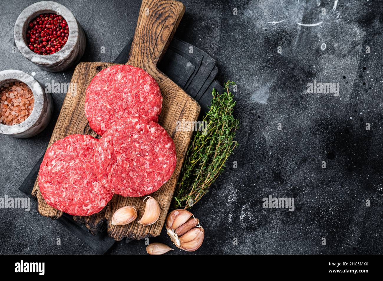 Raw veal hamburger patties with herbs and spices. Black background. Top ...