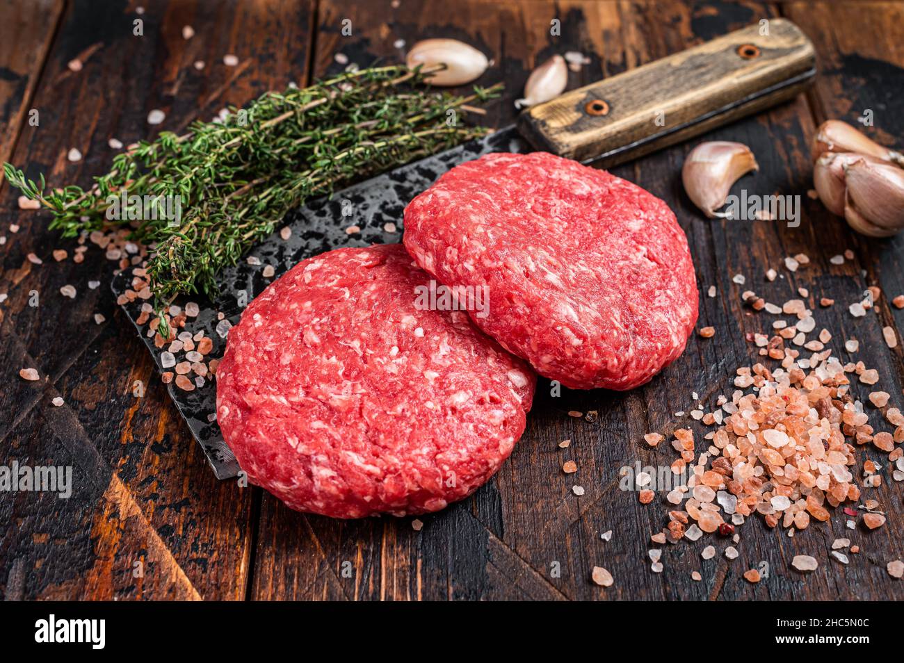 Raw steak cutlets with mince beef meat on a butcher cleaver. Wooden ...