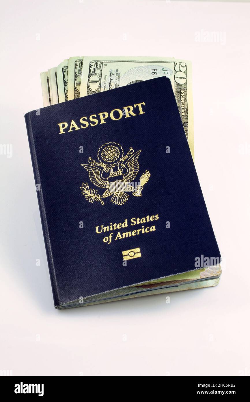 Vertical shot of an American passport with dollar bills on a white ...