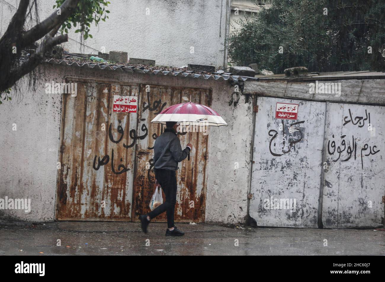 A Palestinian man seen holding an umbrella during a rainy and stormy ...