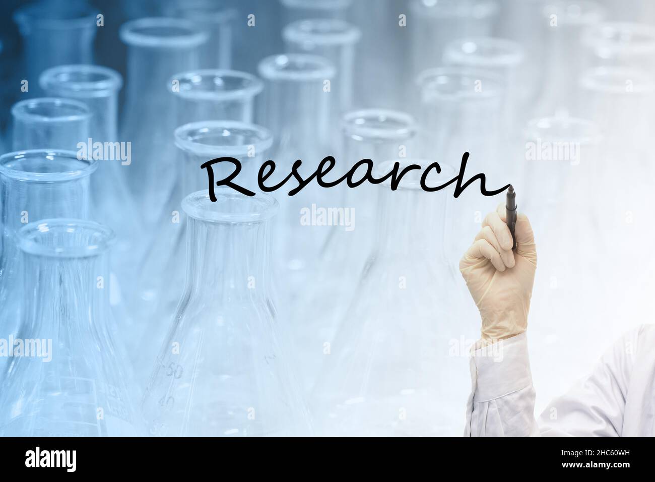 Person writing the word "research" on the background of a bunch of ...