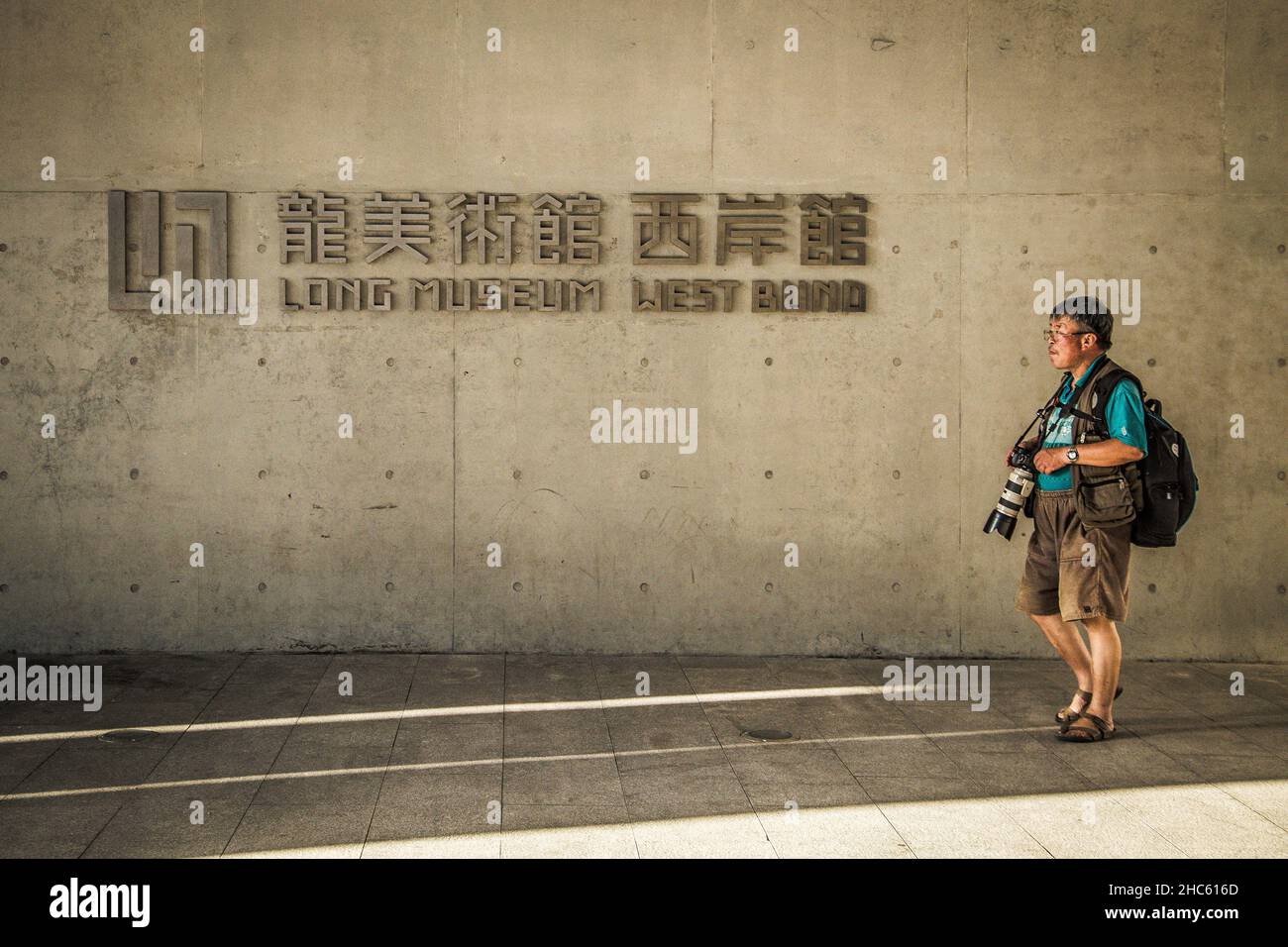 A photographer with a DSLR camera, telephoto lens, and a large camera ...